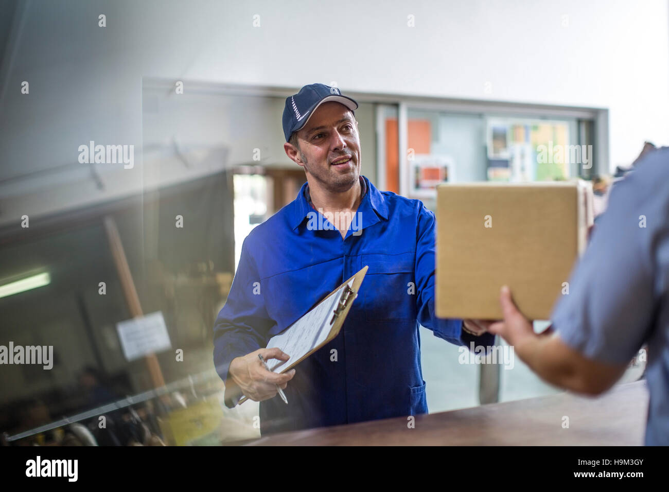 Delivery man handing over cardboard box Stock Photo - Alamy