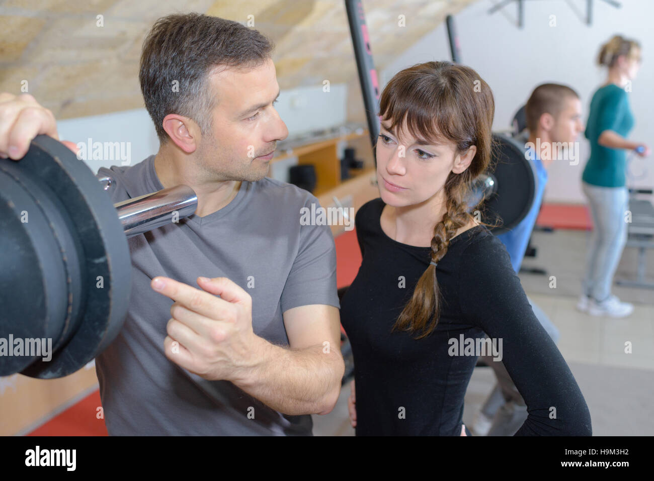 trainer explaining how to use training machine in a gym Stock Photo - Alamy