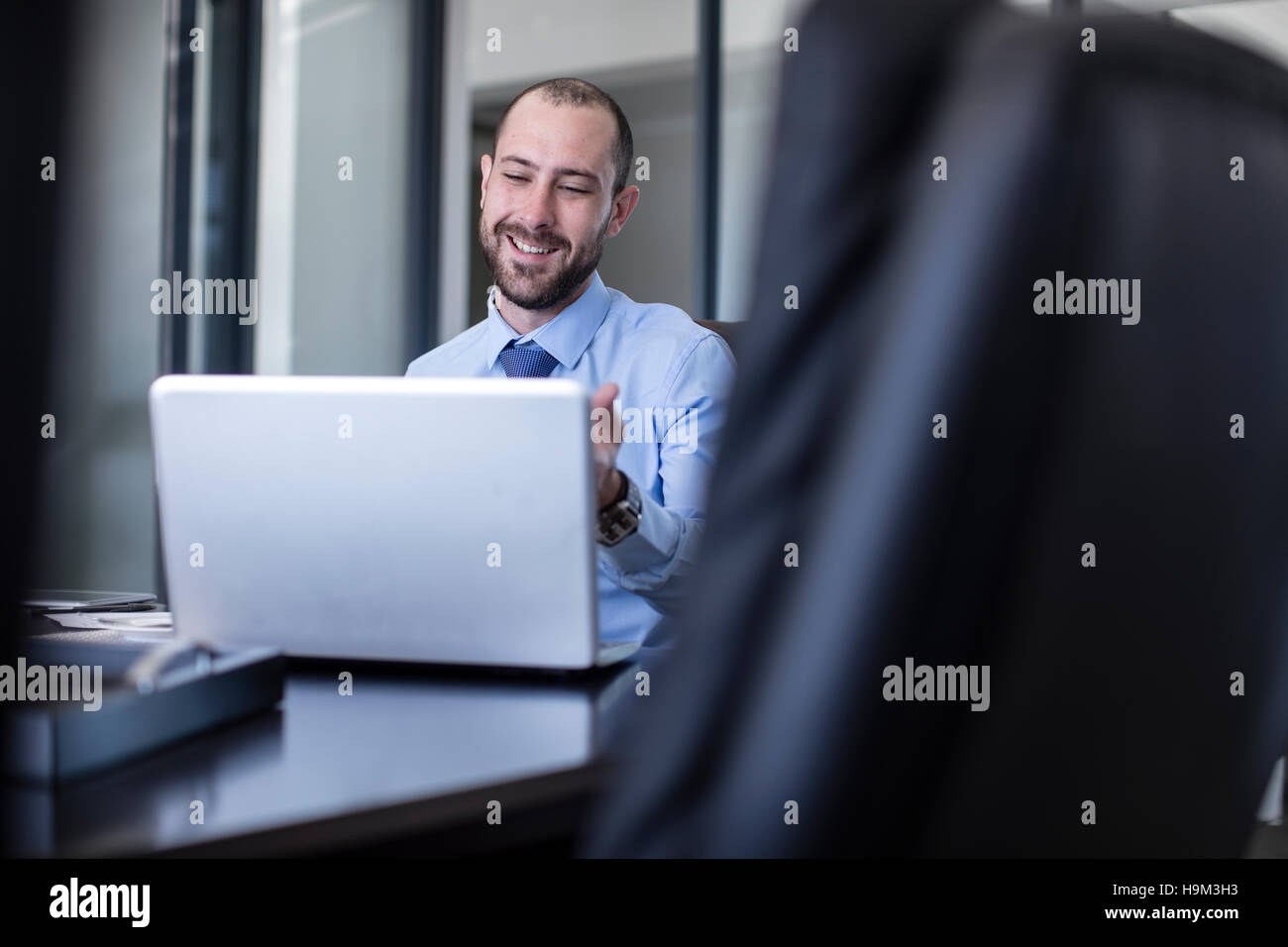 Business man sitting at office desk working on laptop Stock Photo - Alamy