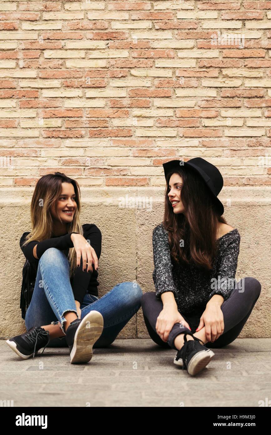 Two best friends sitting in front of facade talking together Stock ...