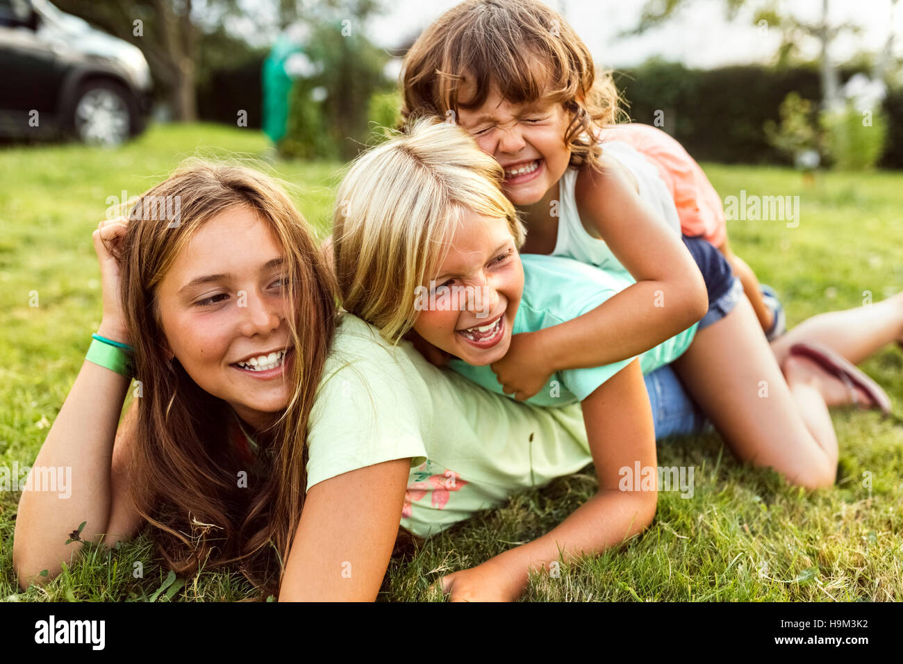 Three girls playing together on a meadow Stock Photo - Alamy