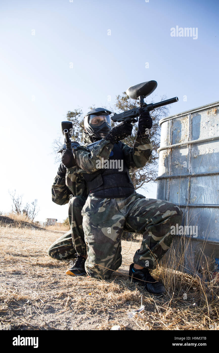 Paintball players aiming with paintball guns during a paintball game ...