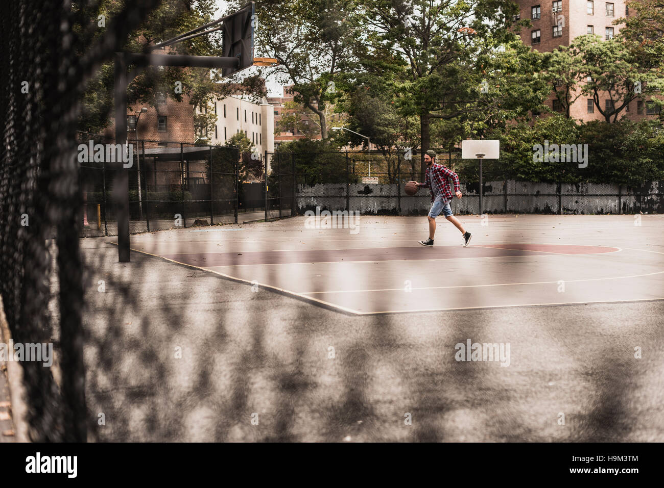 Young man playing basketball on an outdoor court Stock Photo - Alamy