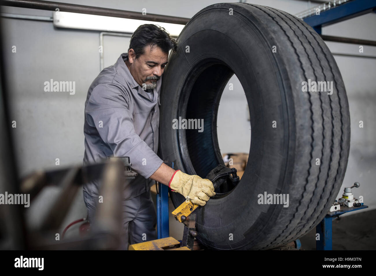 Tire repairer checking tire in factory Stock Photo - Alamy
