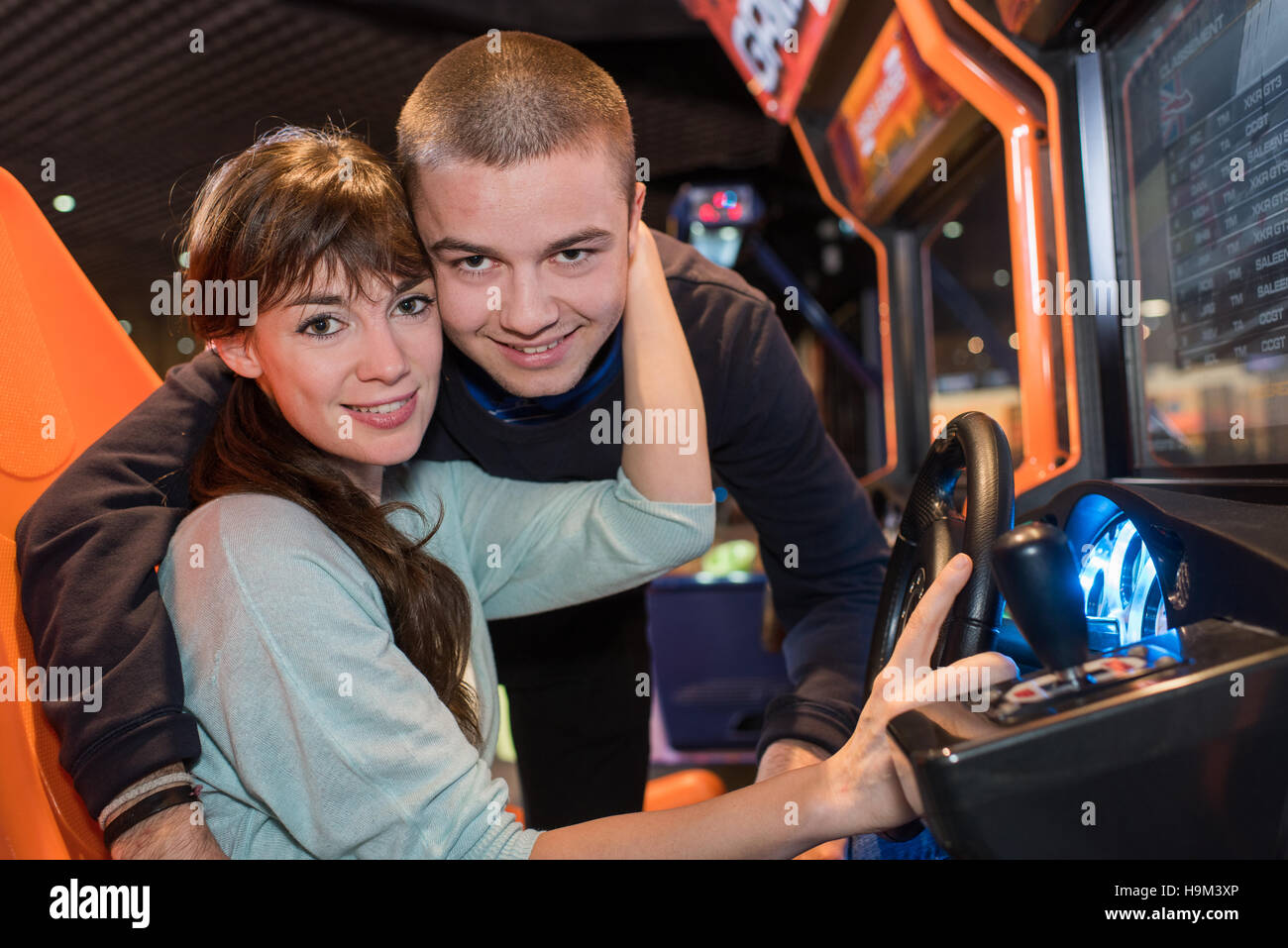 smiling boyfriend playing video games with girlfriend on amusement park ...