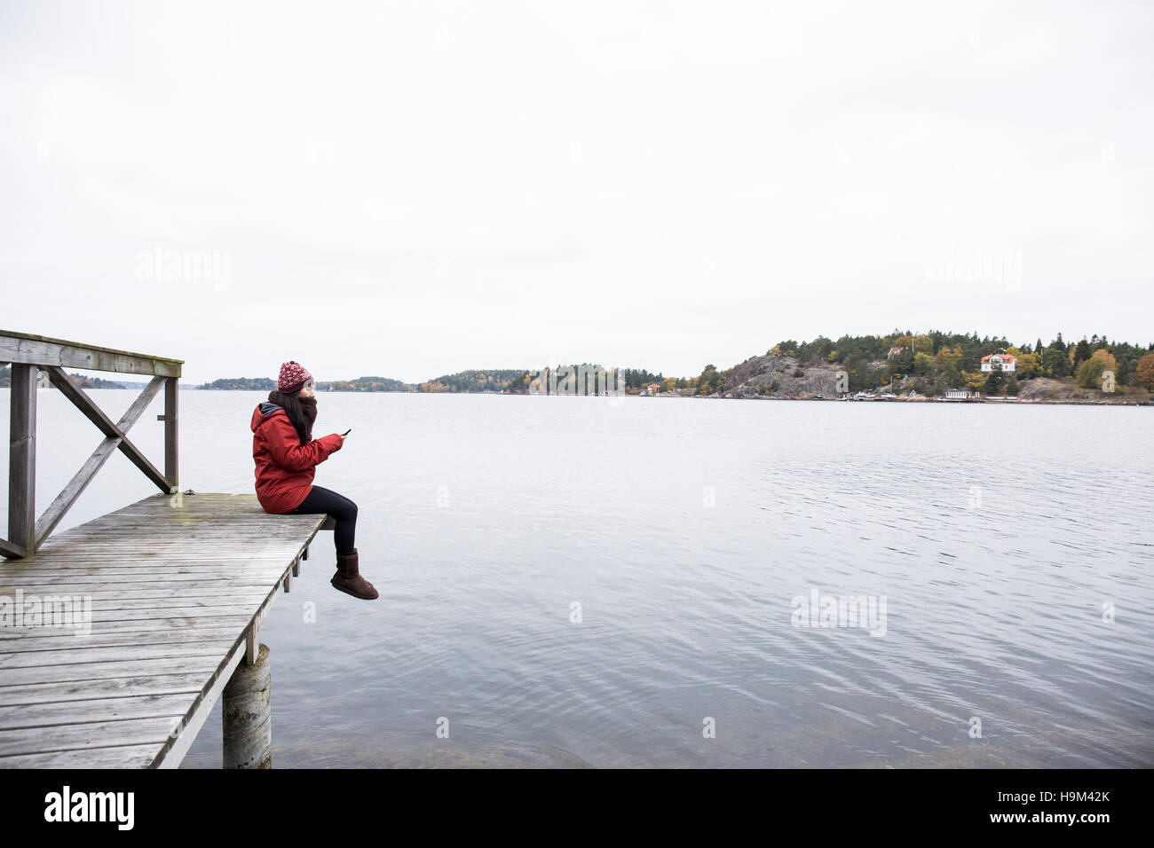 Woman sitting on pier text messaging Stock Photo - Alamy