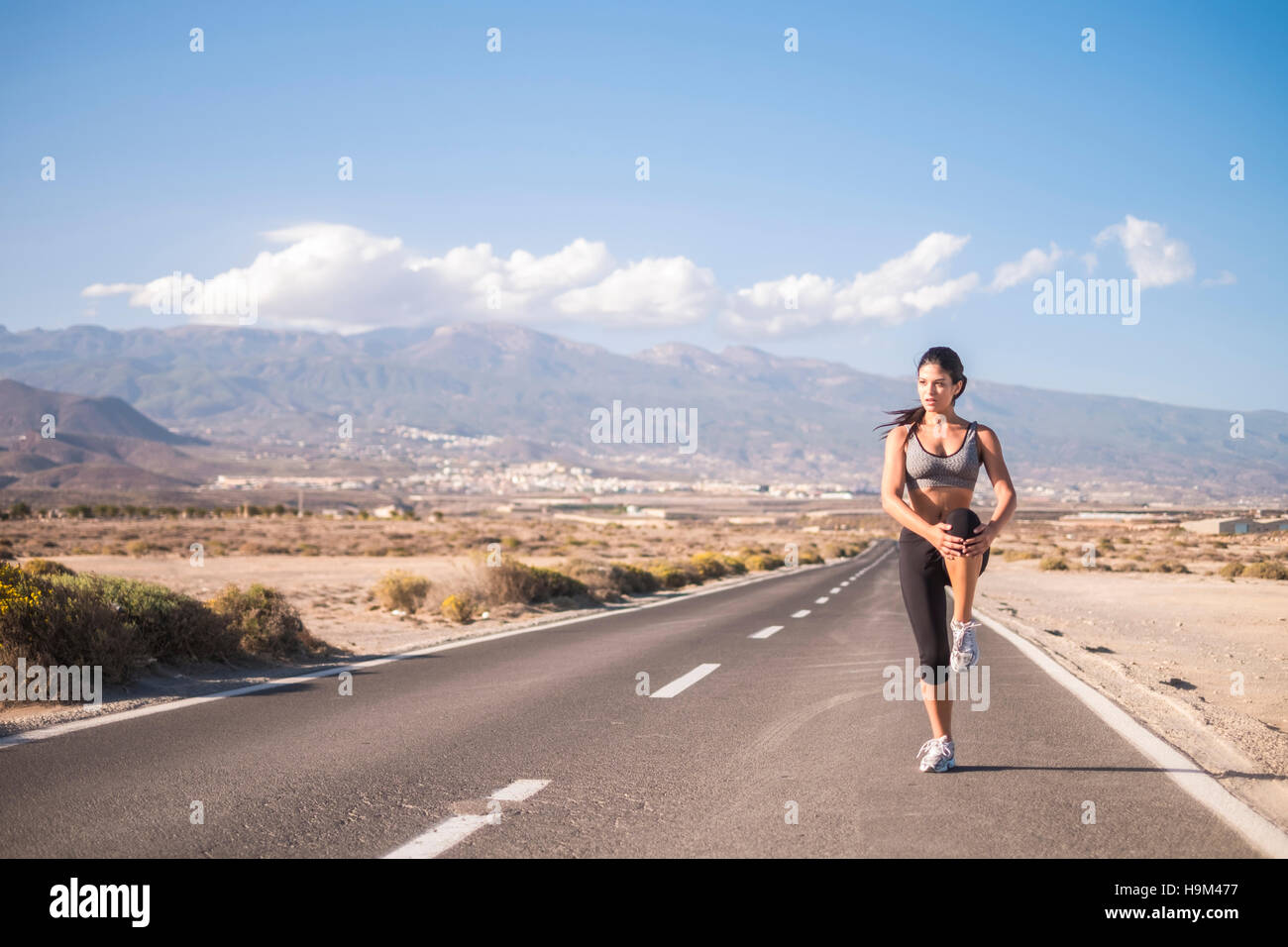 Young woman doing stretching exercises on an empty road Stock Photo - Alamy