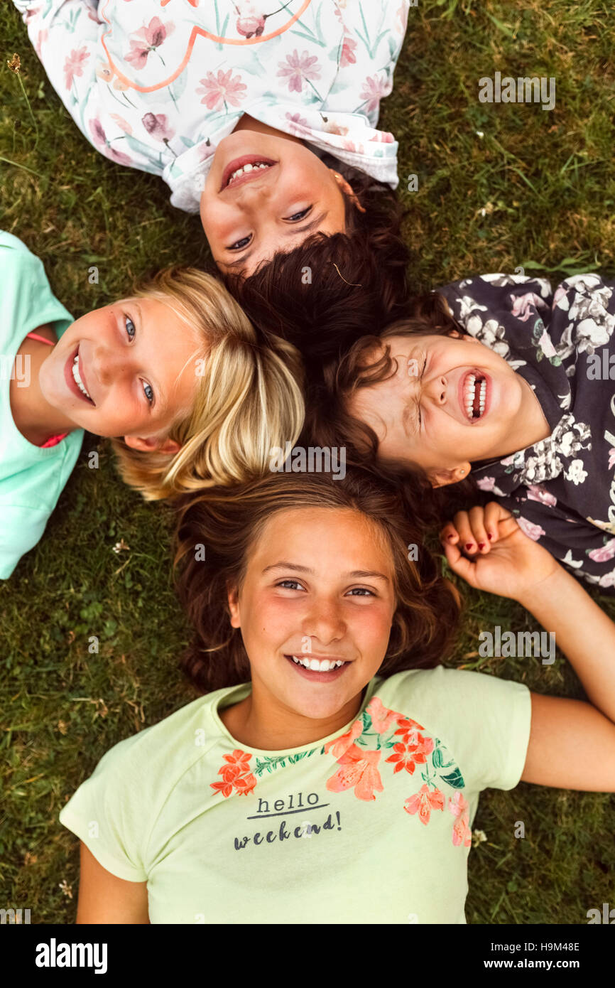Four laughing girls lying head to head on a meadow Stock Photo - Alamy