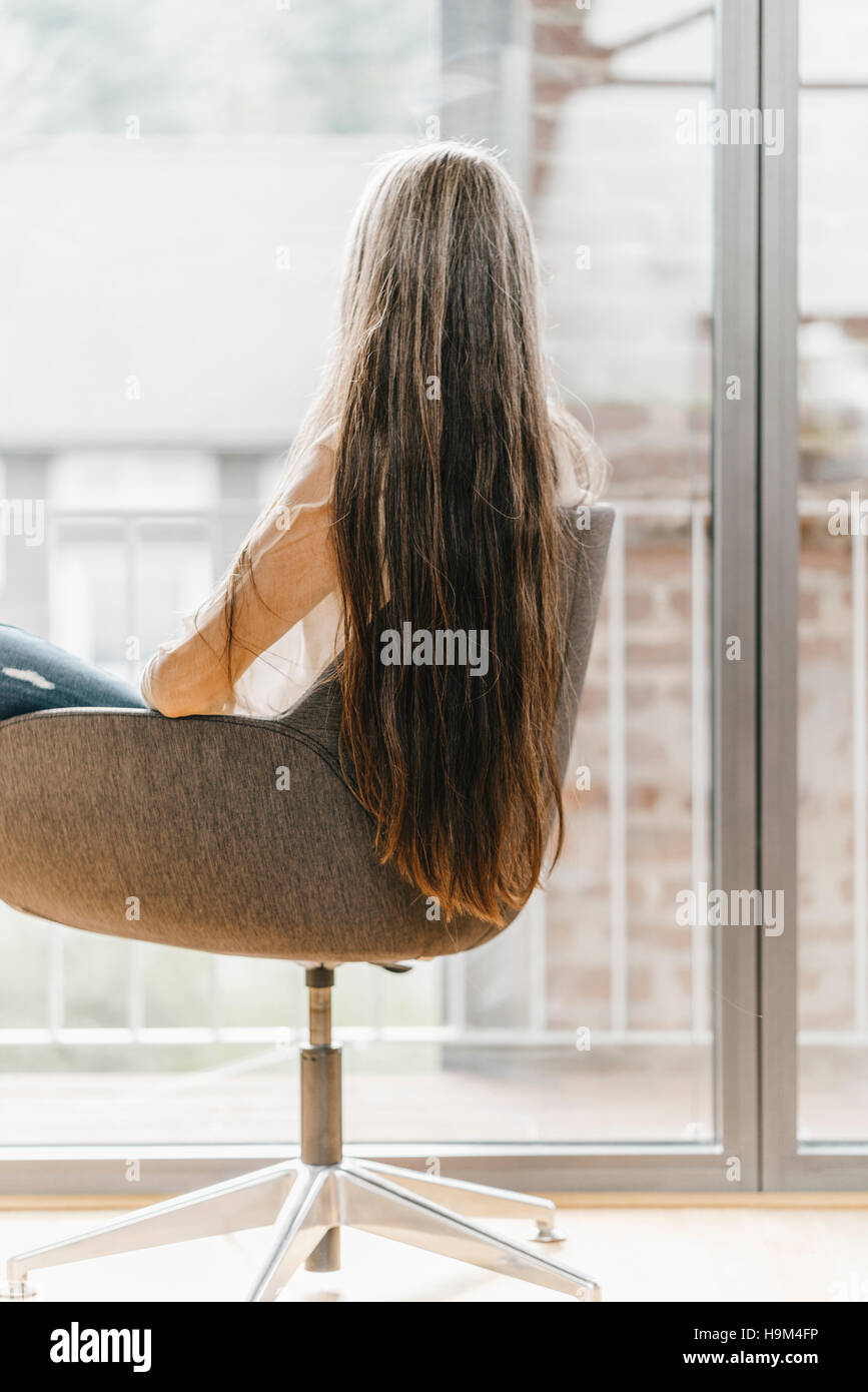 Woman with long grey hair sitting on chair at the window Stock Photo ...