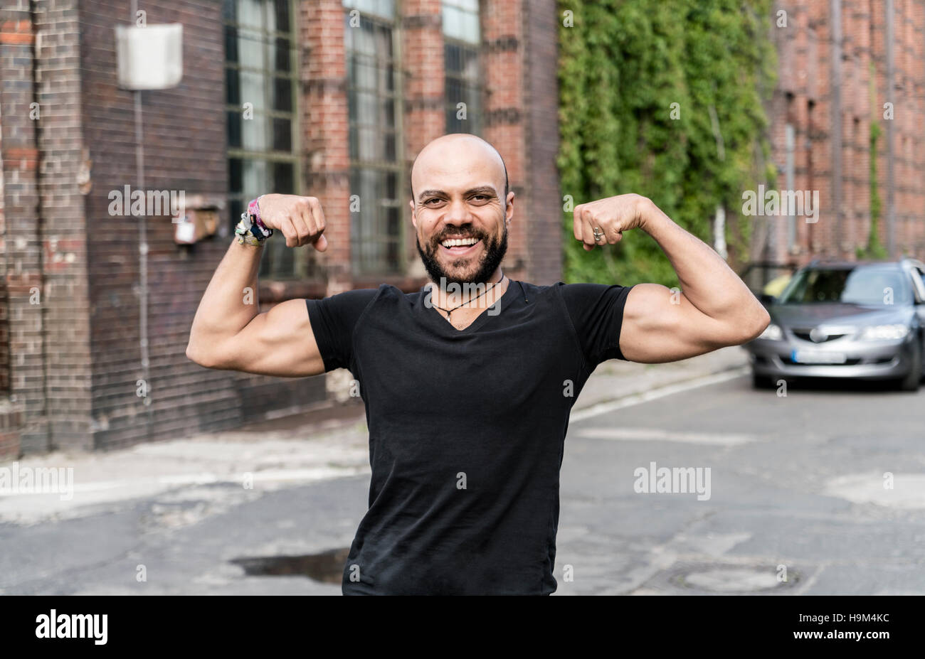 Portrait of smiling man flexing muscles Stock Photo - Alamy