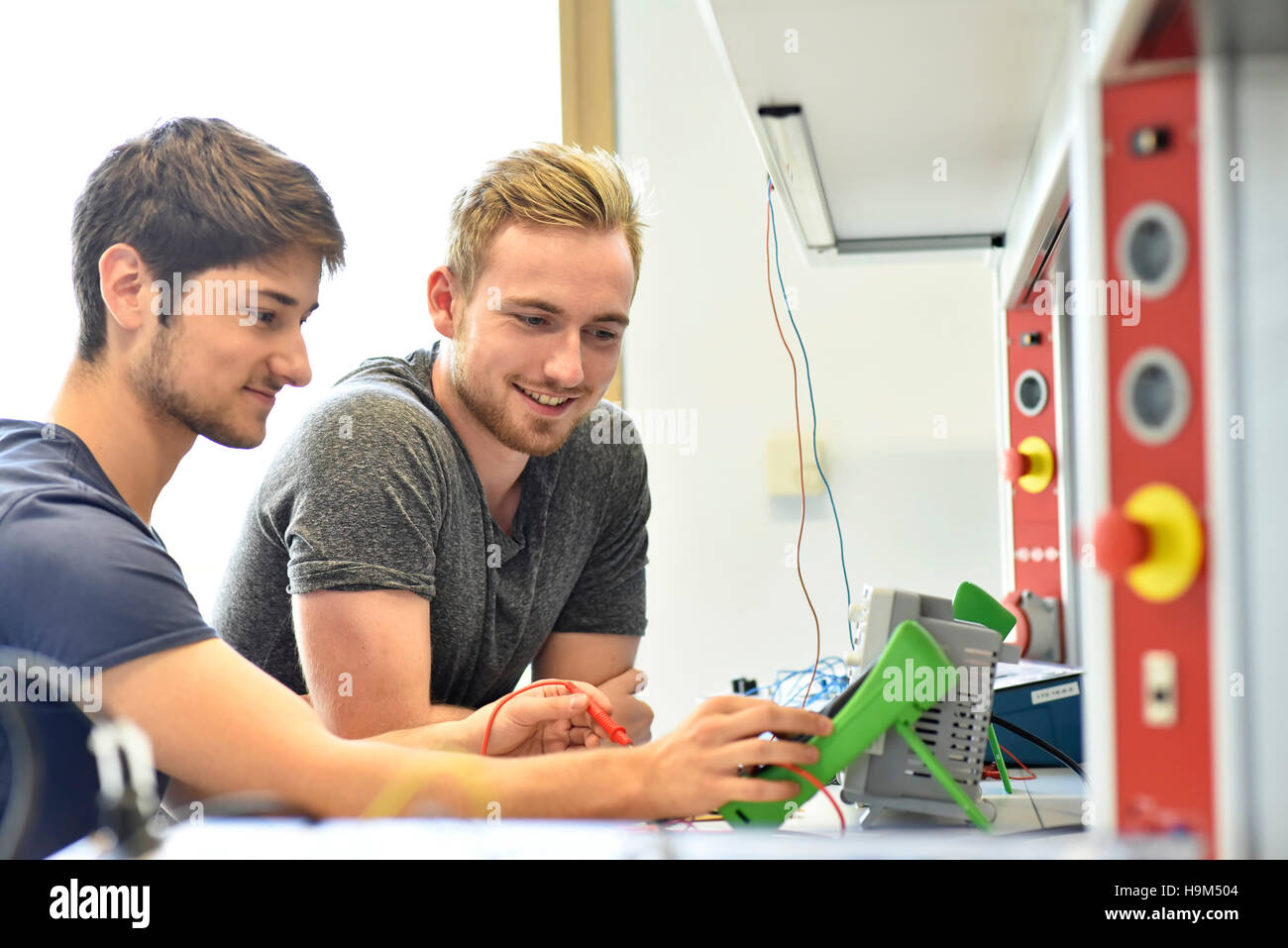 Smiling technical students looking at device Stock Photo - Alamy