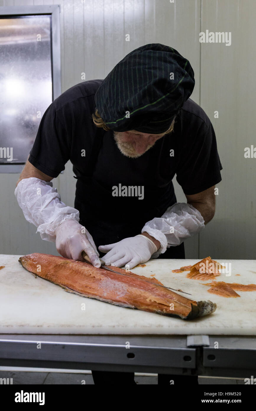 Fish smoker cleaning freshly smoked salmon with a knife Stock Photo - Alamy