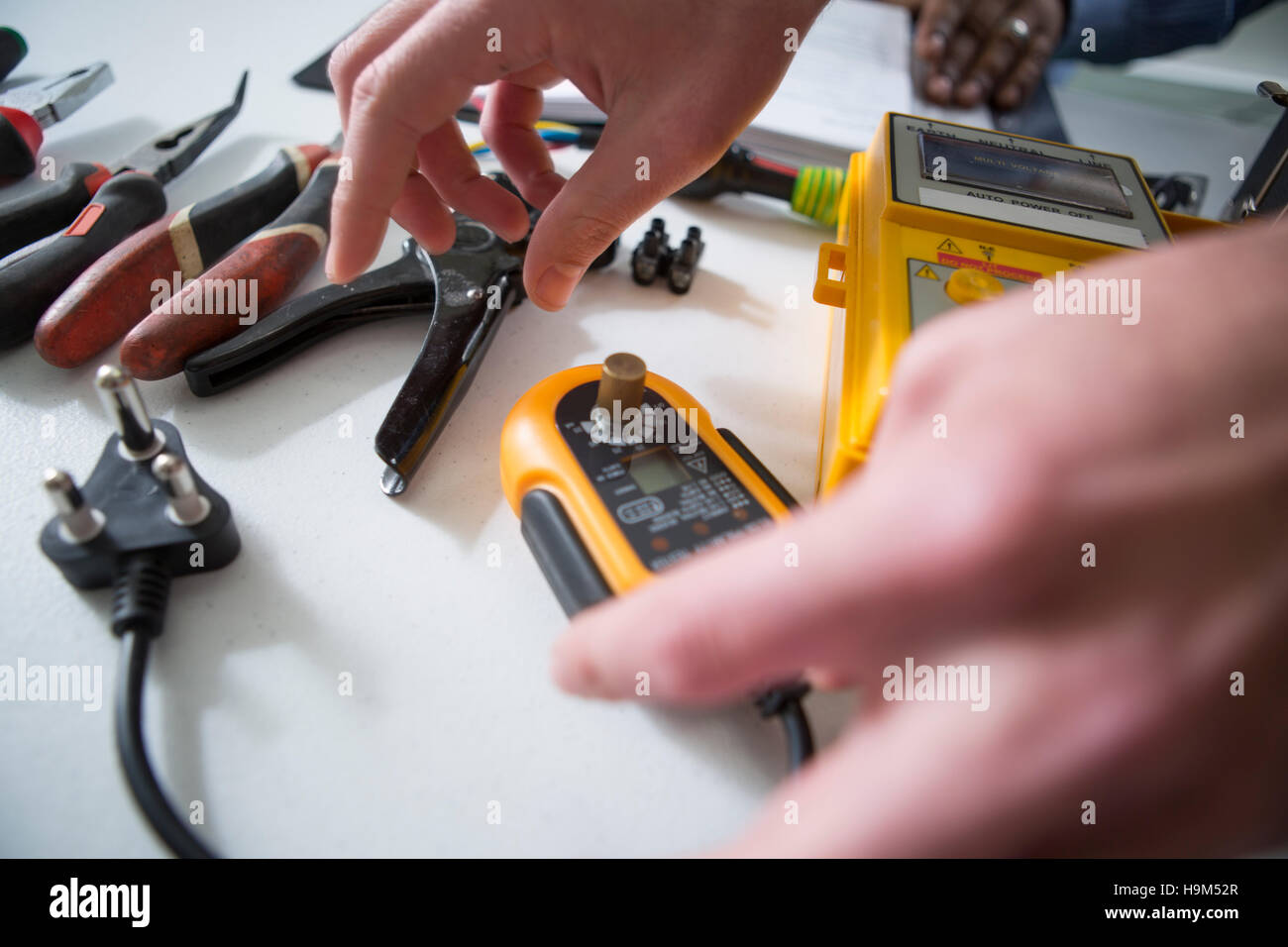 Hands and table with electrician tools Stock Photo - Alamy