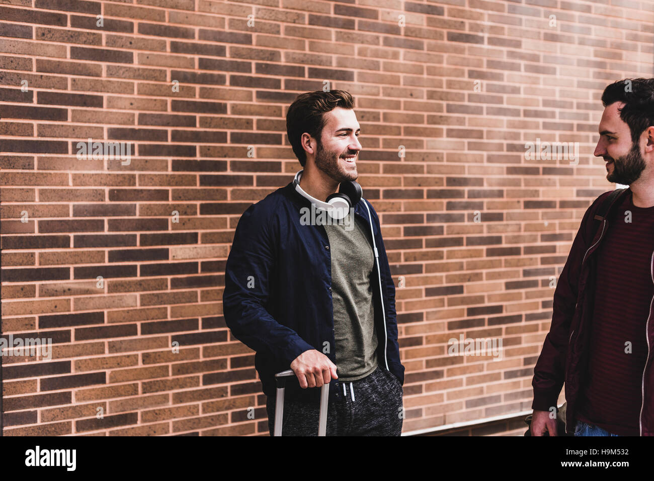Two smiling friends at brick wall Stock Photo - Alamy