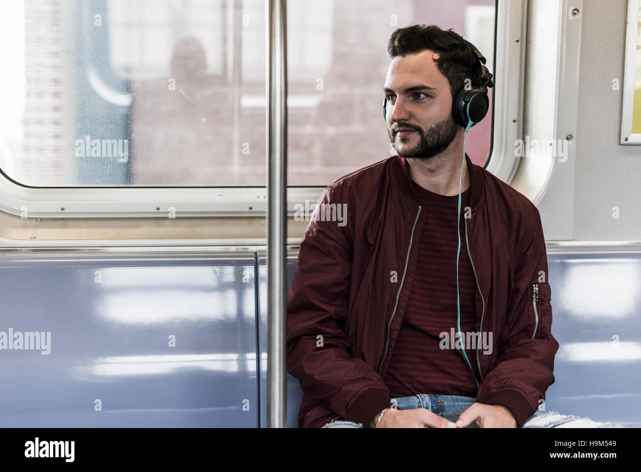 Young man sitting in subway wearing headphones Stock Photo - Alamy