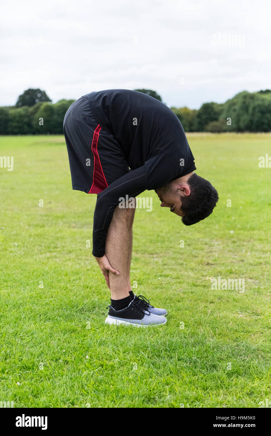 Athlete stretching in grass Stock Photo - Alamy