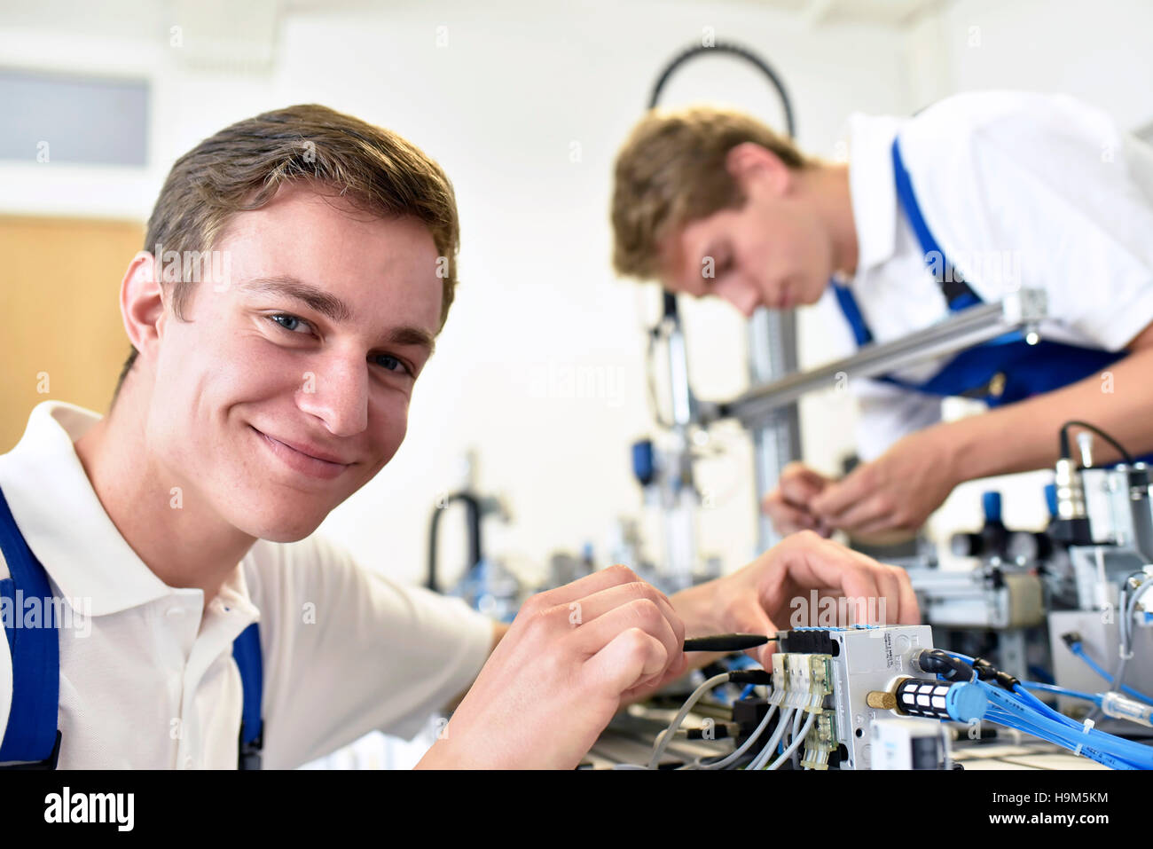 Portrait of smiling student working with pneumatics component parts ...