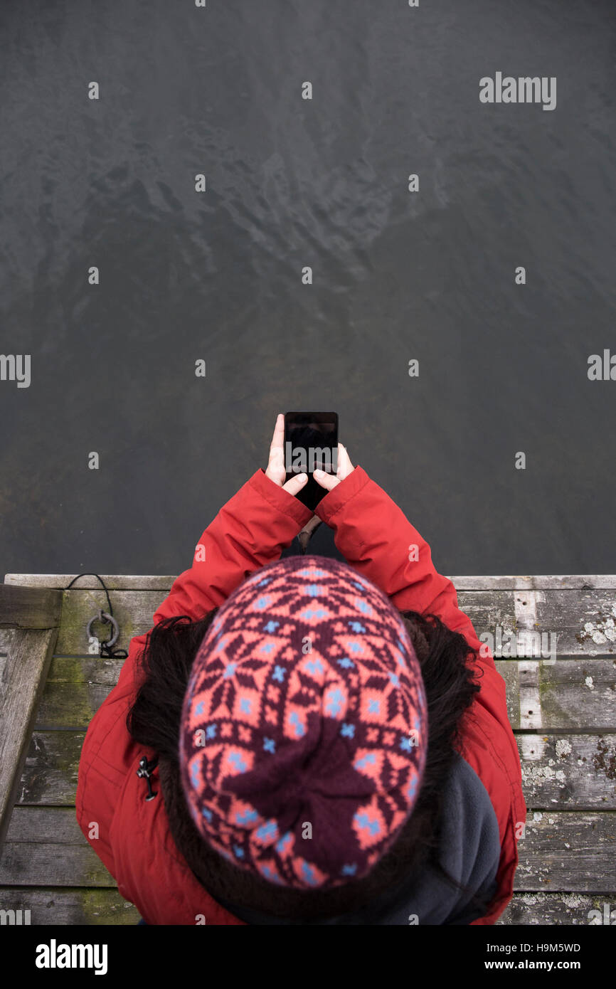 Top view of woman sitting on pier text messaging Stock Photo - Alamy