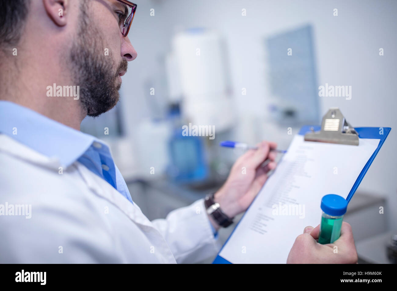 Scientist with clipboard and test tube working in laboratory Stock ...