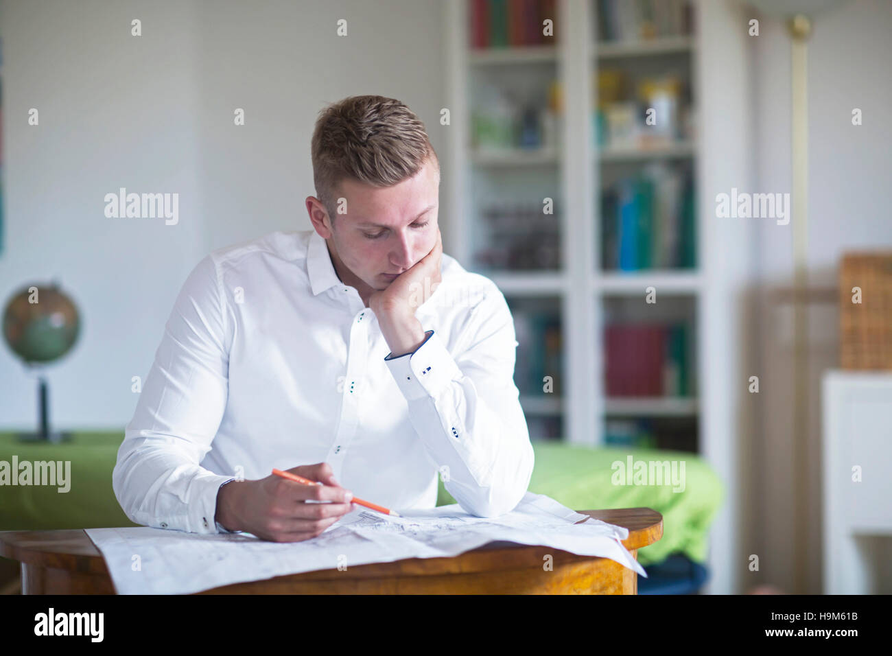Young man looking at construction plan at desk Stock Photo - Alamy