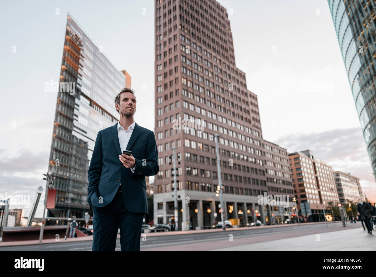 Germany, Berlin, businessman with smartphone standing at Potsdamer ...