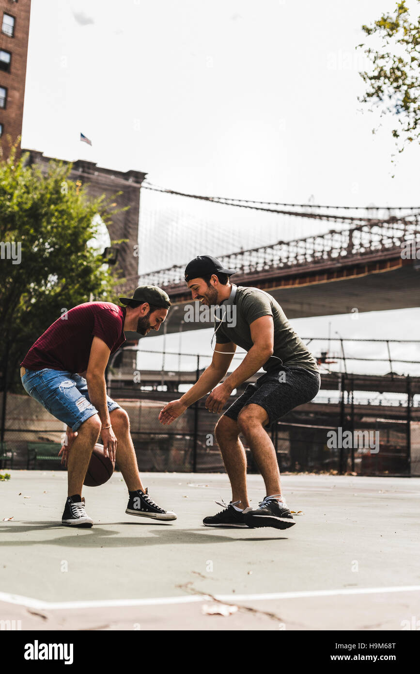 USA, New York, two young men playing basketball on an outdoor court ... USA, New York, two young men playing basketball on an outdoor court ...