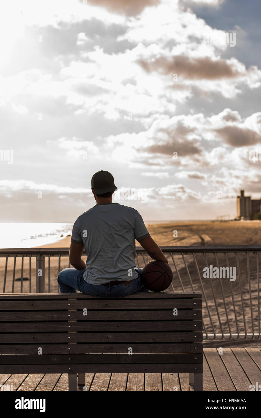 USA, New York City, man sitting on bridge on Coney Island with ...
