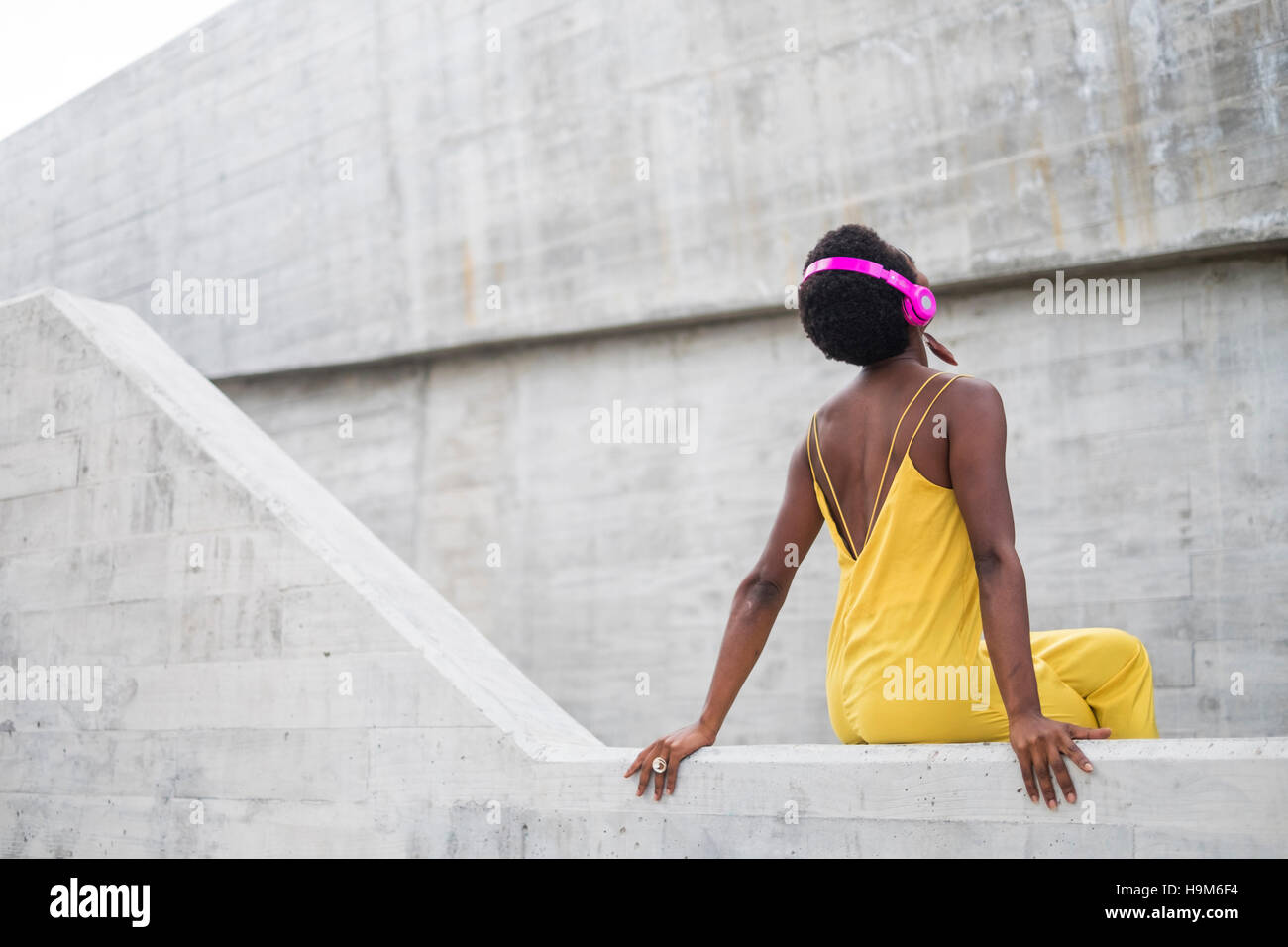 Back view of woman listening music with pink headphones Stock Photo - Alamy