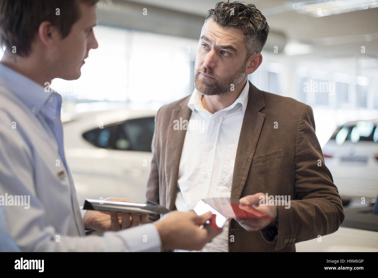 Car dealer handing over color sample to client in showroom Stock Photo ...