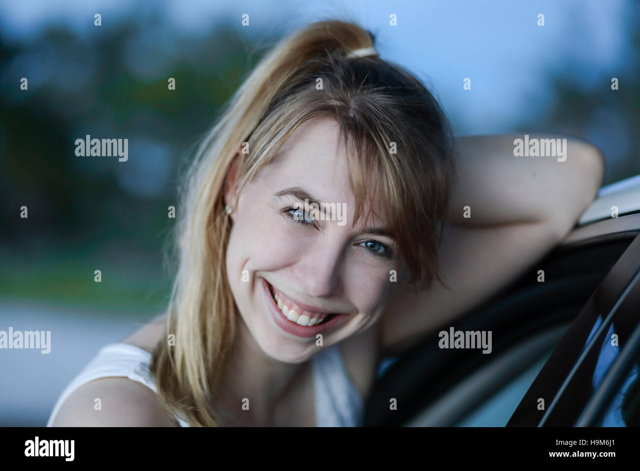 Smiling woman leaning against car, portrait Stock Photo - Alamy