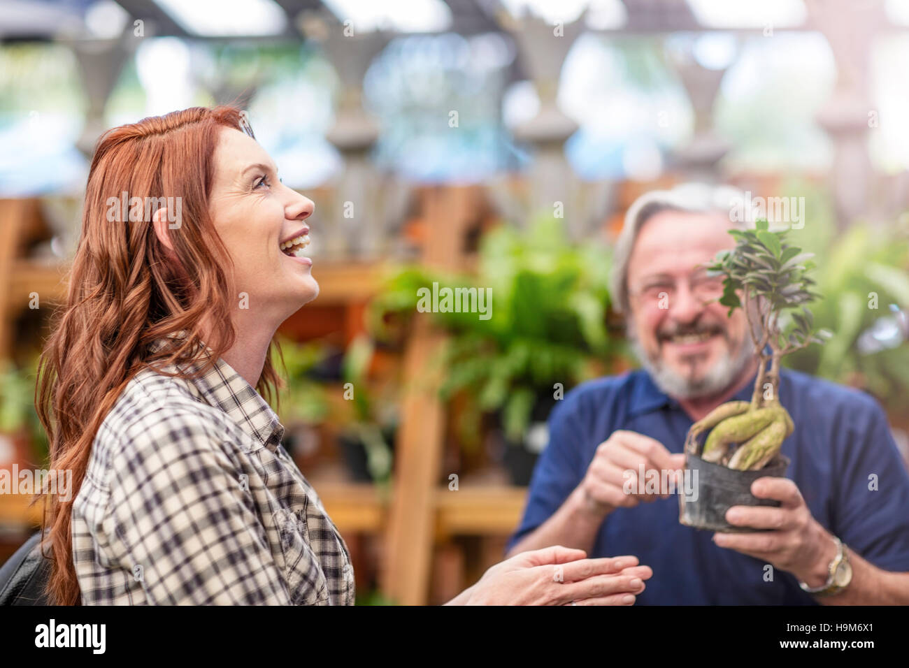 Gardener helping woman at garden centre Stock Photo - Alamy