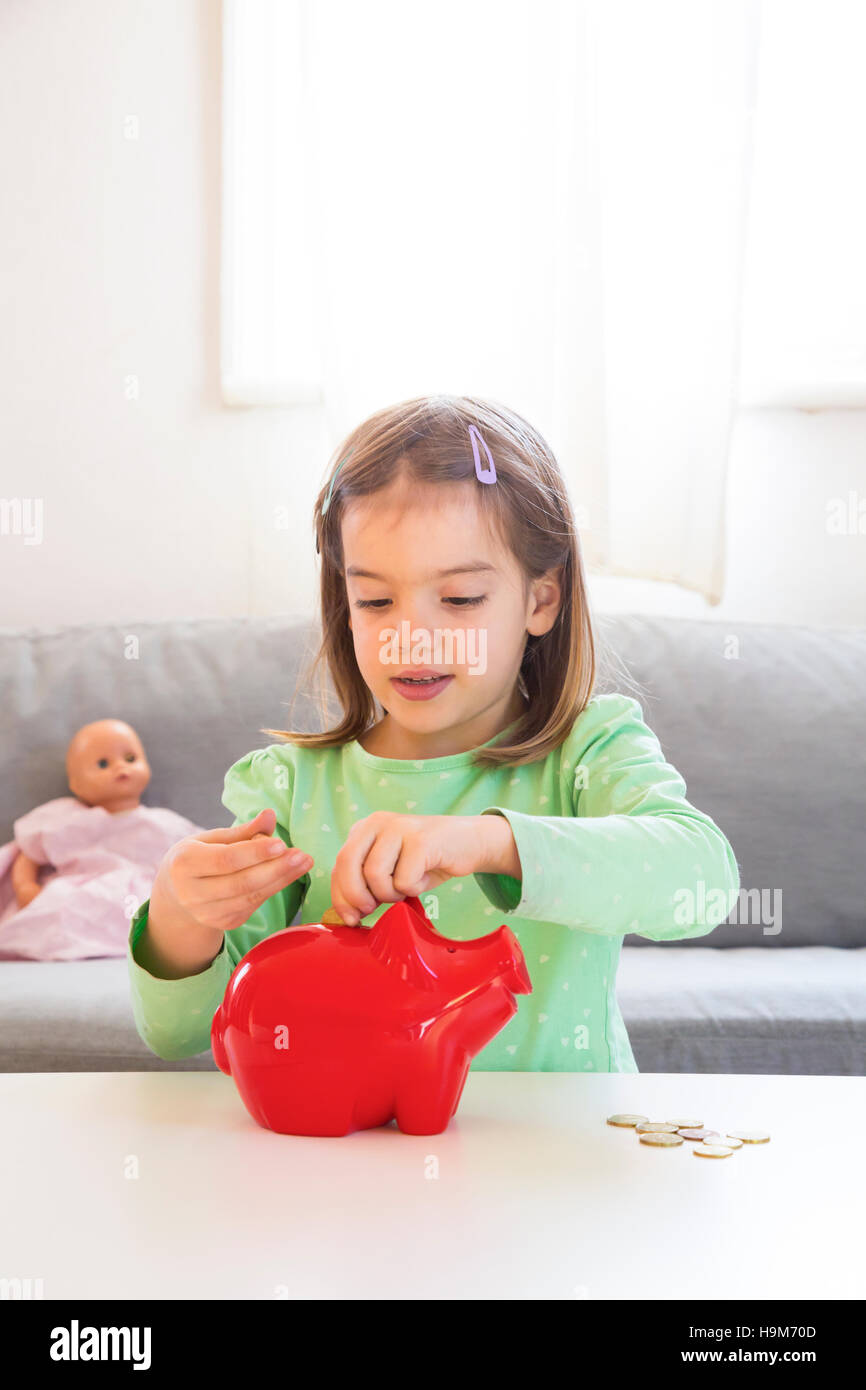Girl putting coin into piggy bank Stock Photo - Alamy