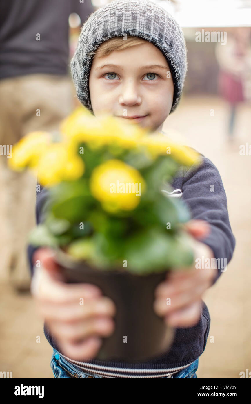 Boy holding yellow flower pot Stock Photo - Alamy