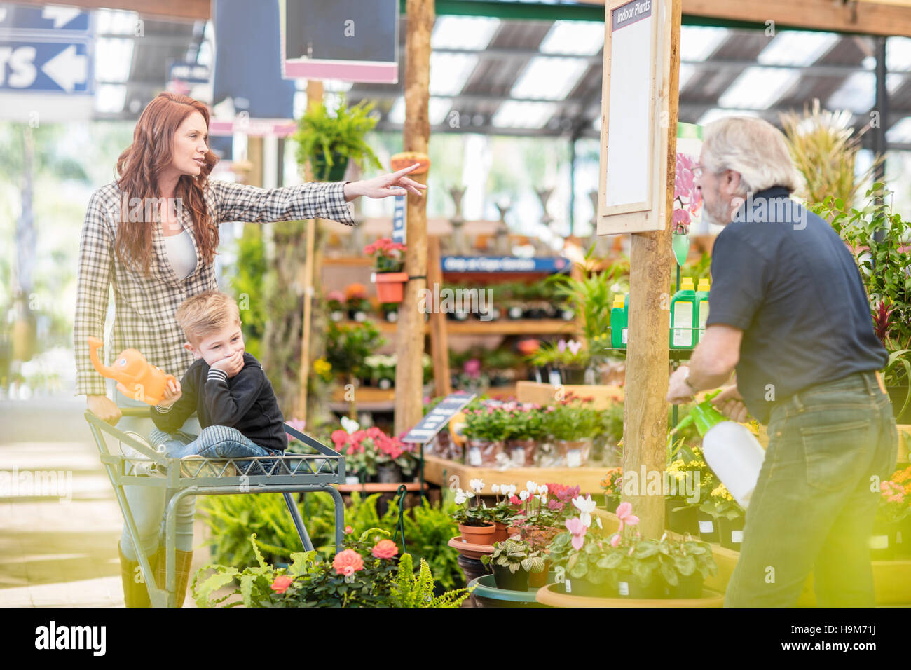 Gardener helping clients at garden centre Stock Photo - Alamy