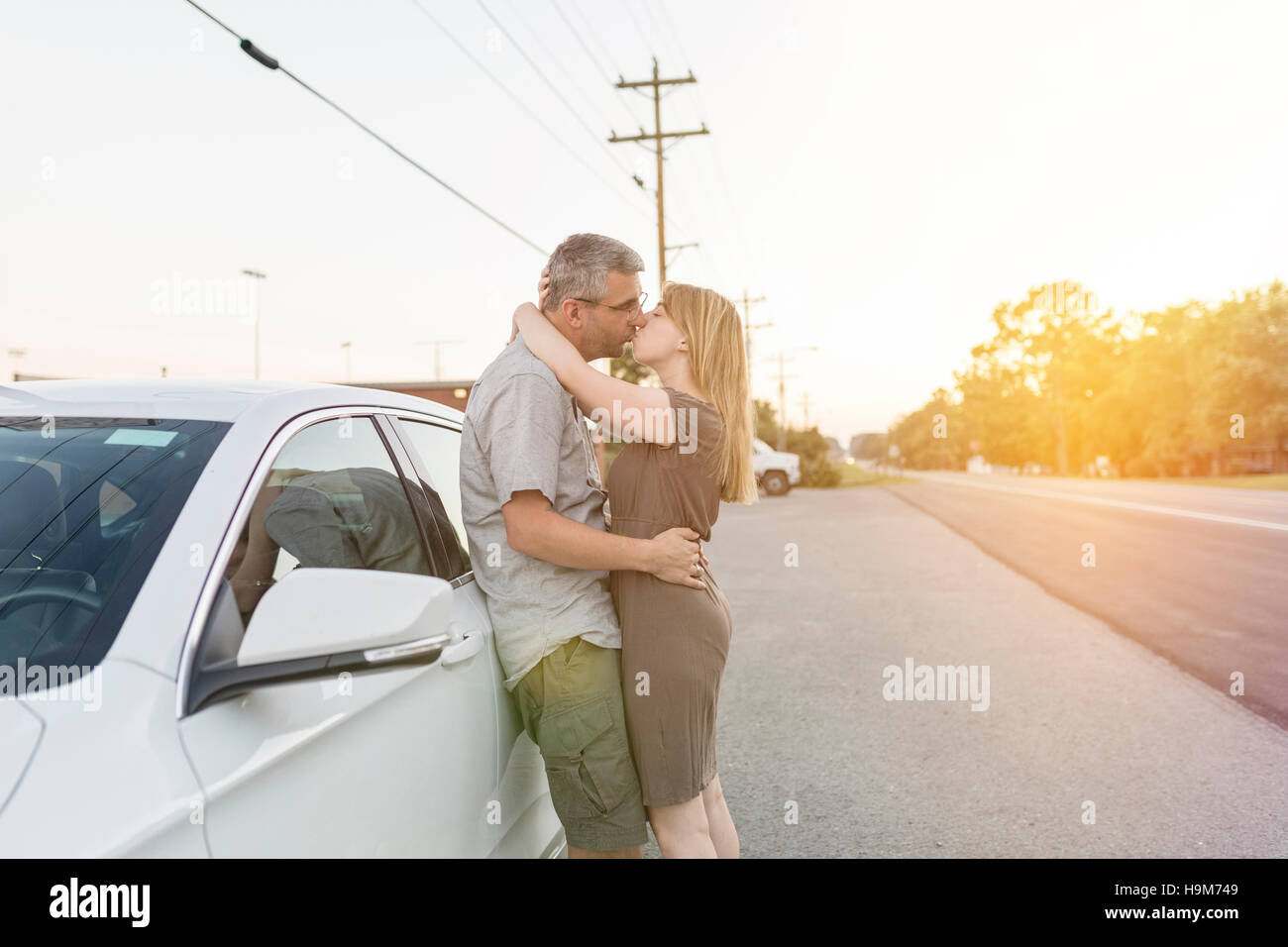 Couple on a road trip taking a break kissing each other Stock Photo - Alamy