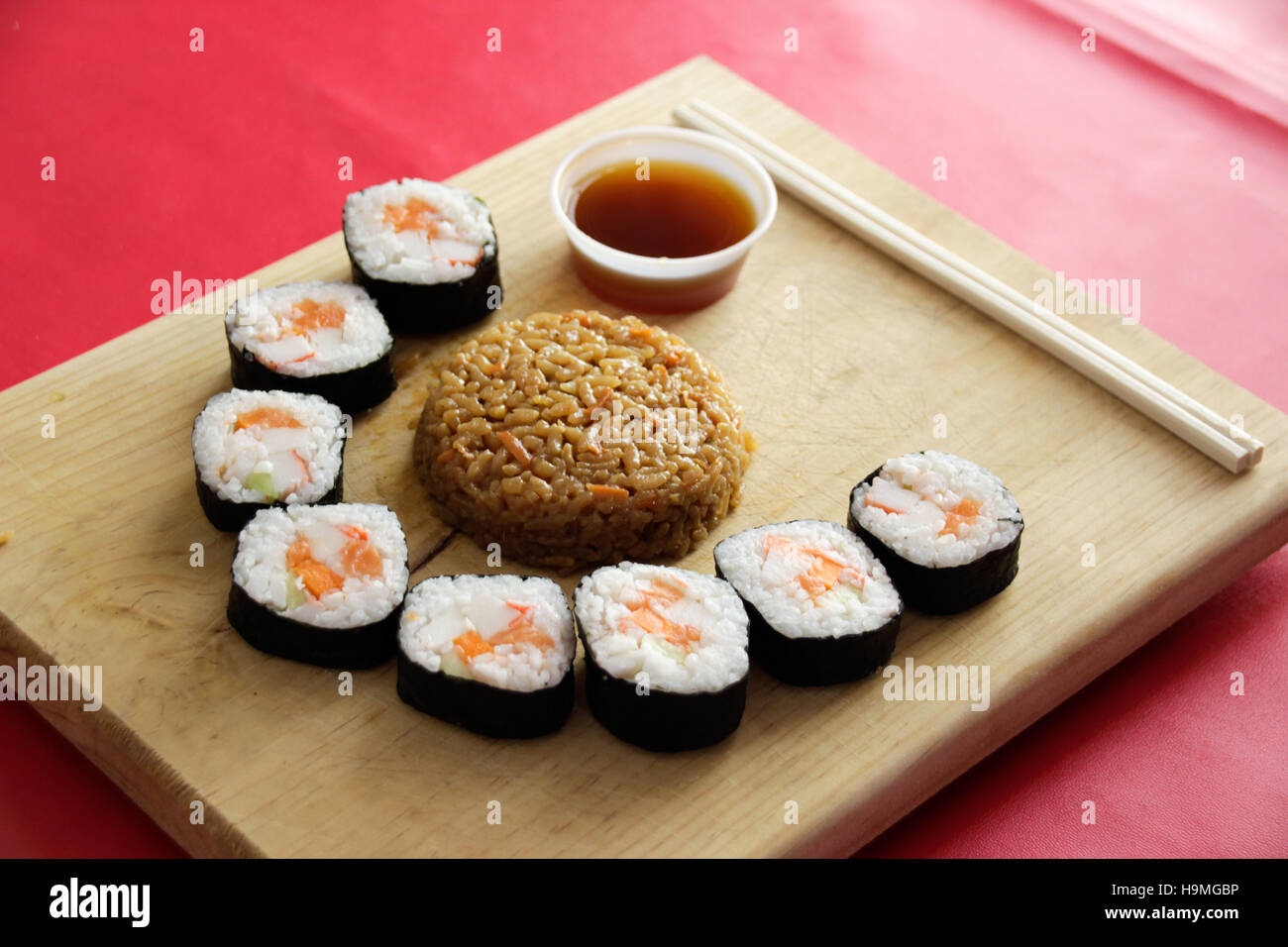 Phtograph of some Sushi roll slices and fried rice on a wood table ...