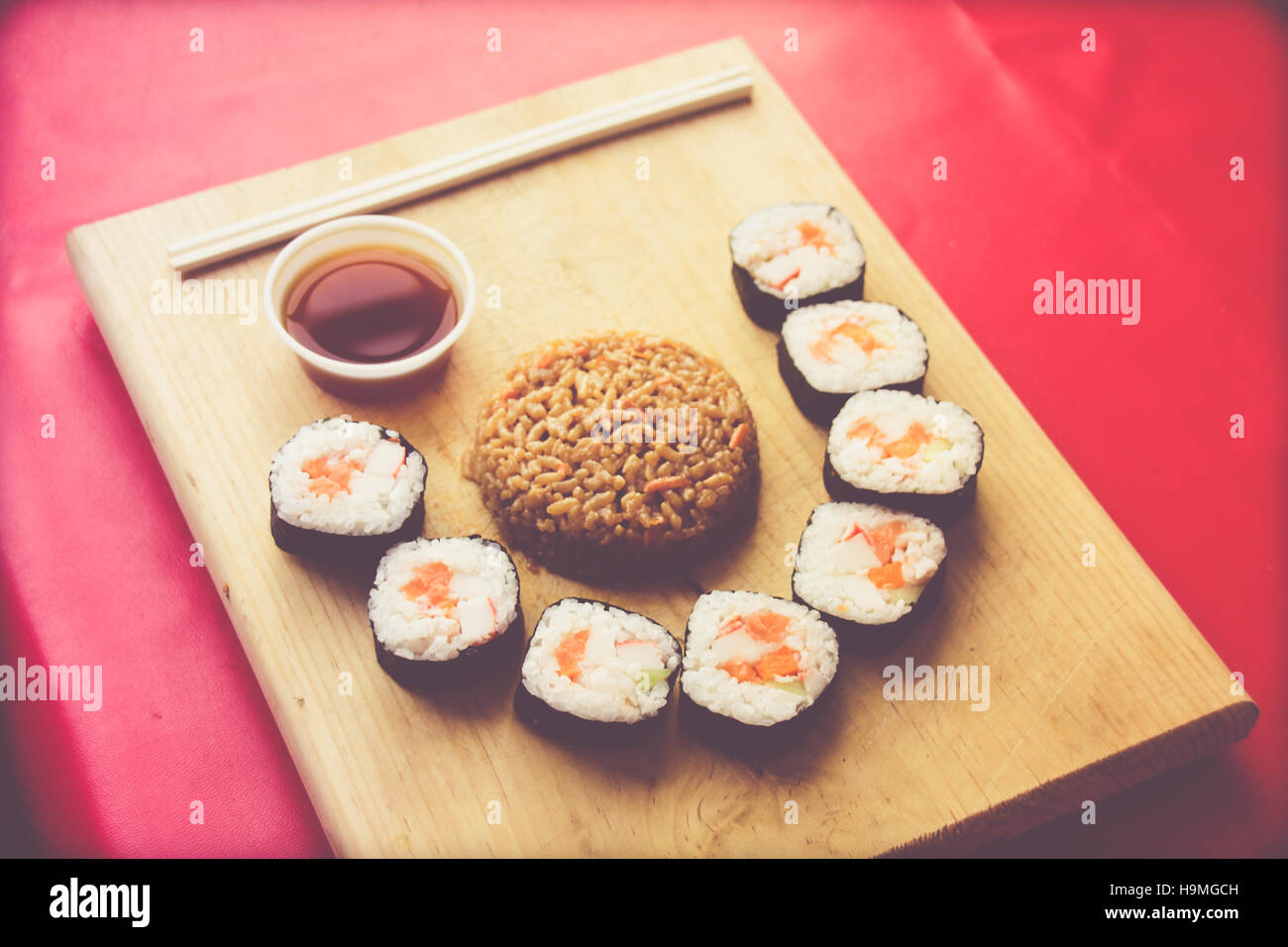 Phtograph of some Sushi roll slices and fried rice on a wood table ...