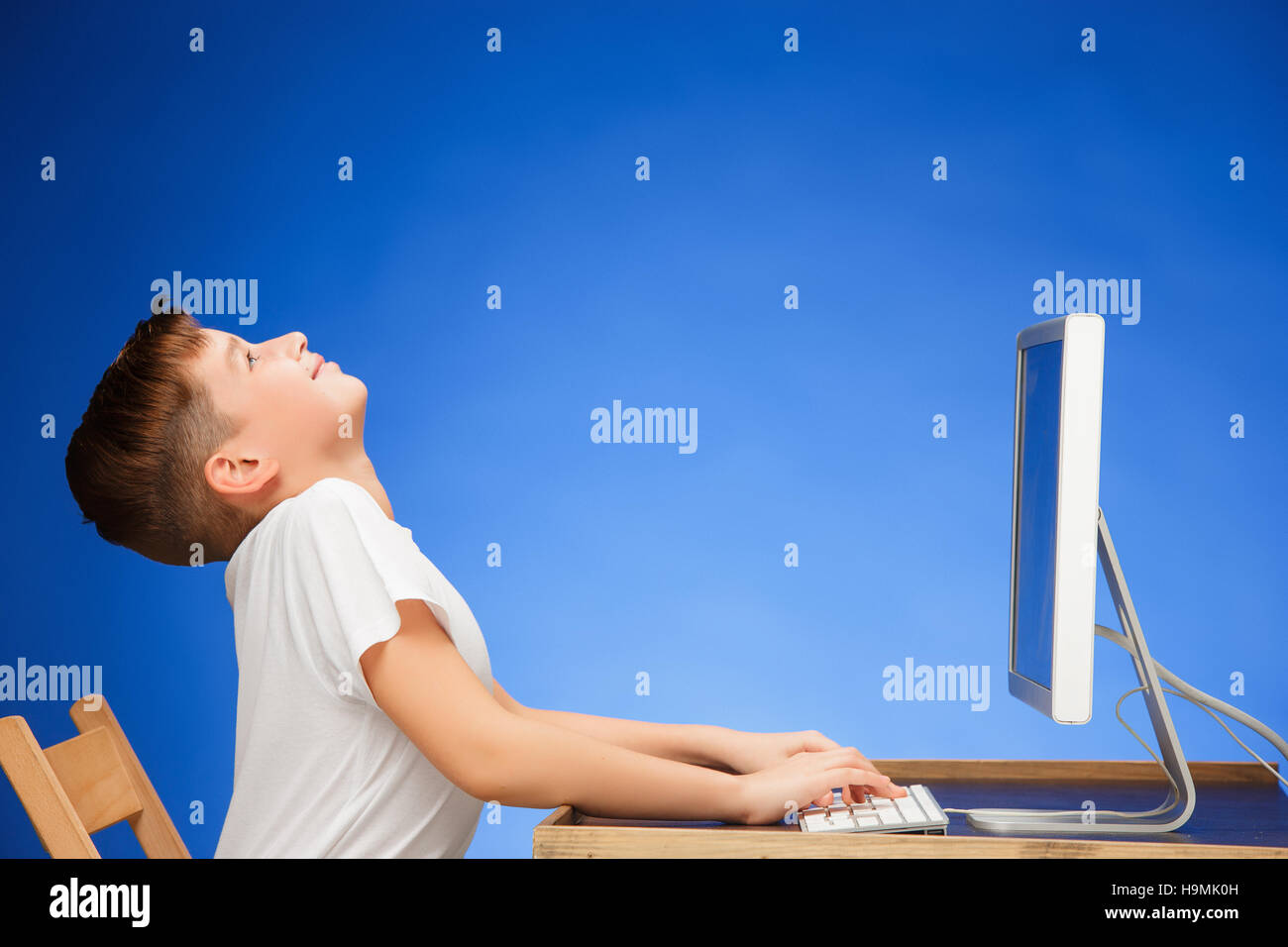 School-age boy sitting in front of the monitor laptop at studio Stock ...