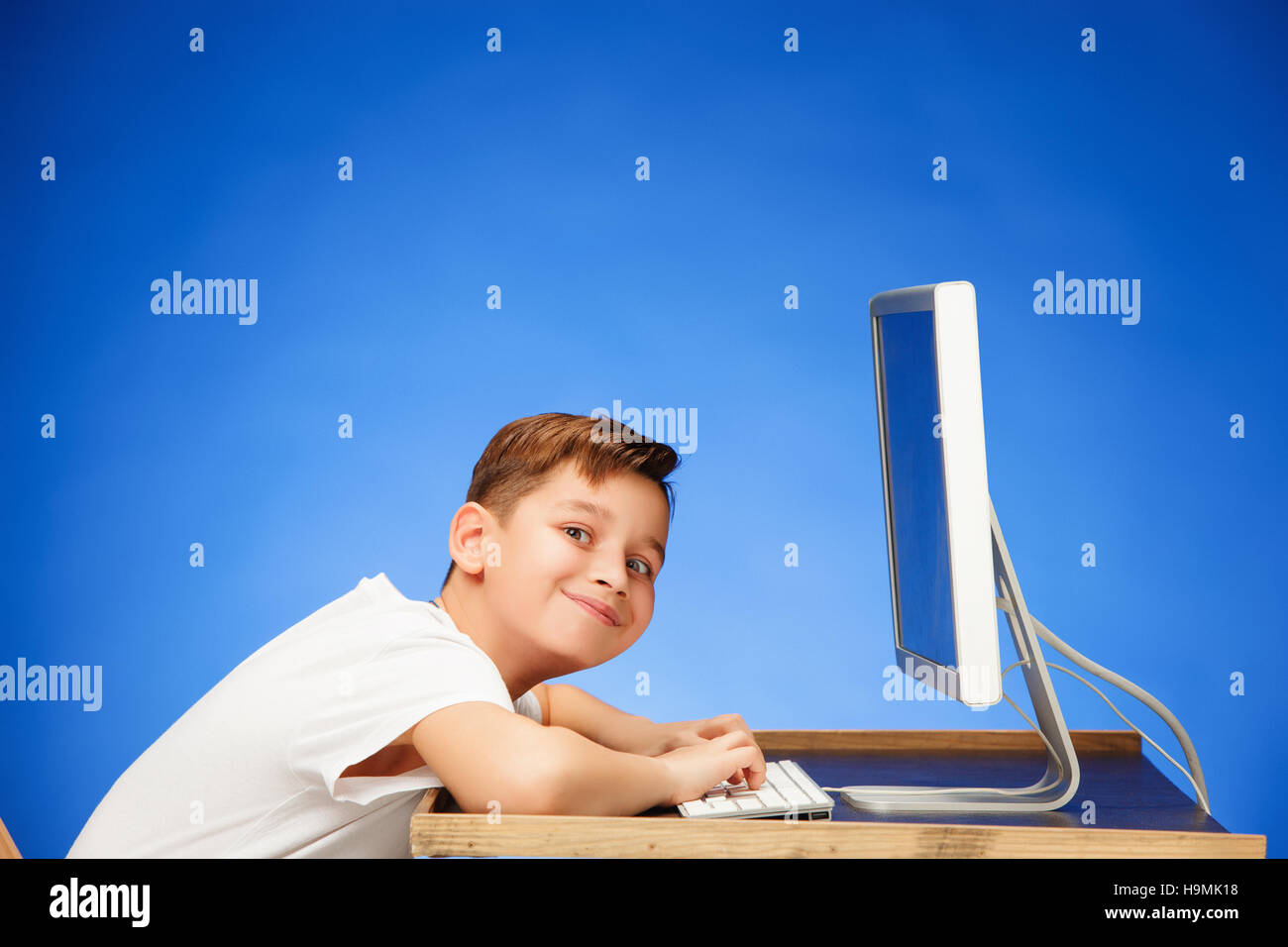 School-age boy sitting in front of the monitor laptop at studio Stock ...