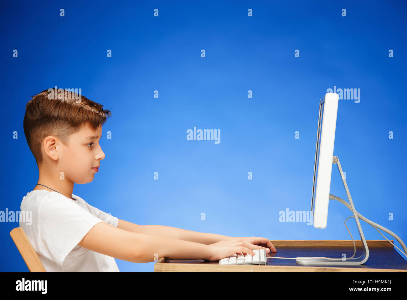 School-age boy sitting in front of the monitor laptop at studio Stock ...