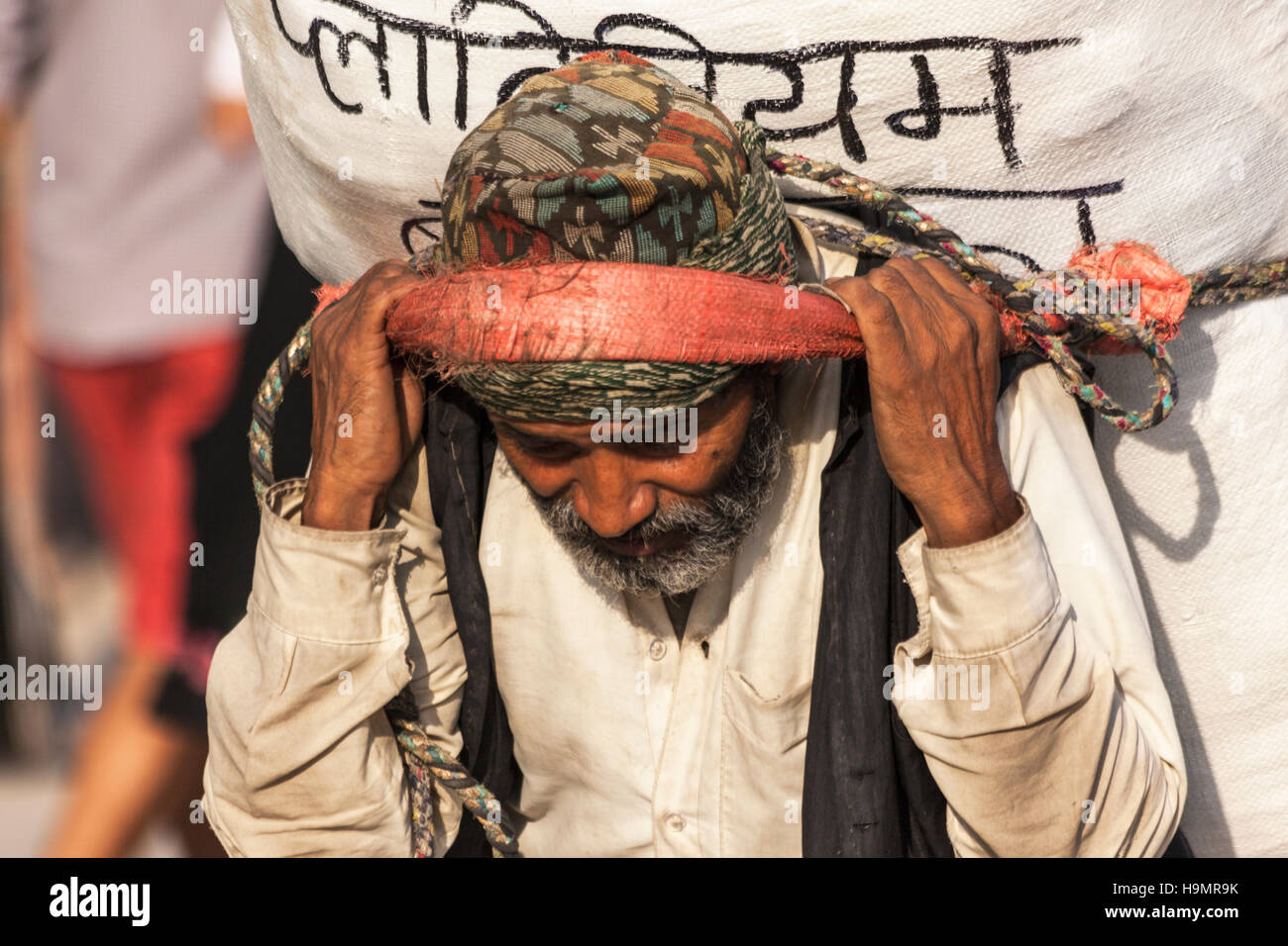 Man carrying a heavy load on his back with ahead brace Stock Photo - Alamy