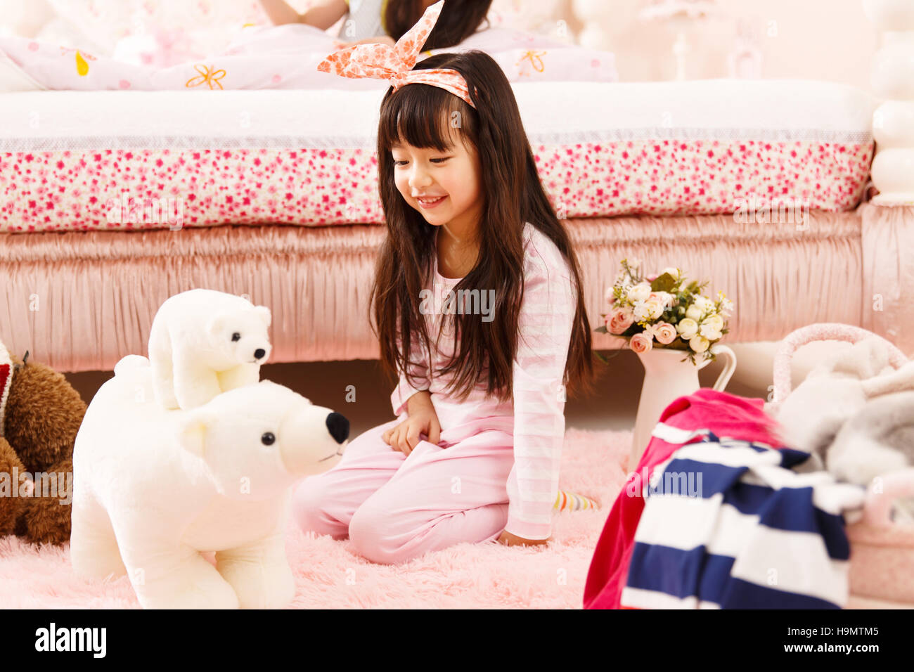 Cute little girl sitting on the rug Stock Photo - Alamy
