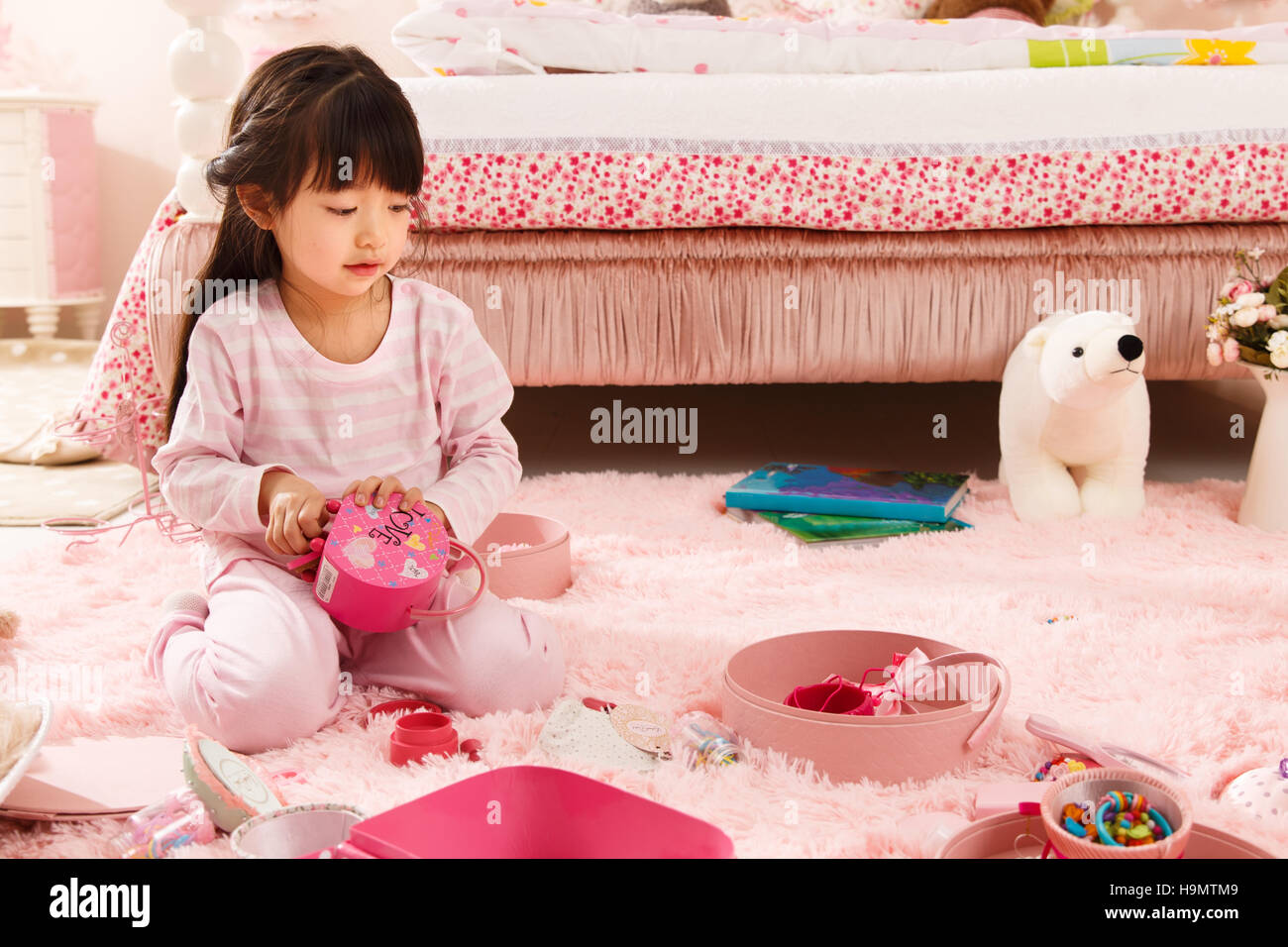 Cute little girl sitting on the rug Stock Photo - Alamy