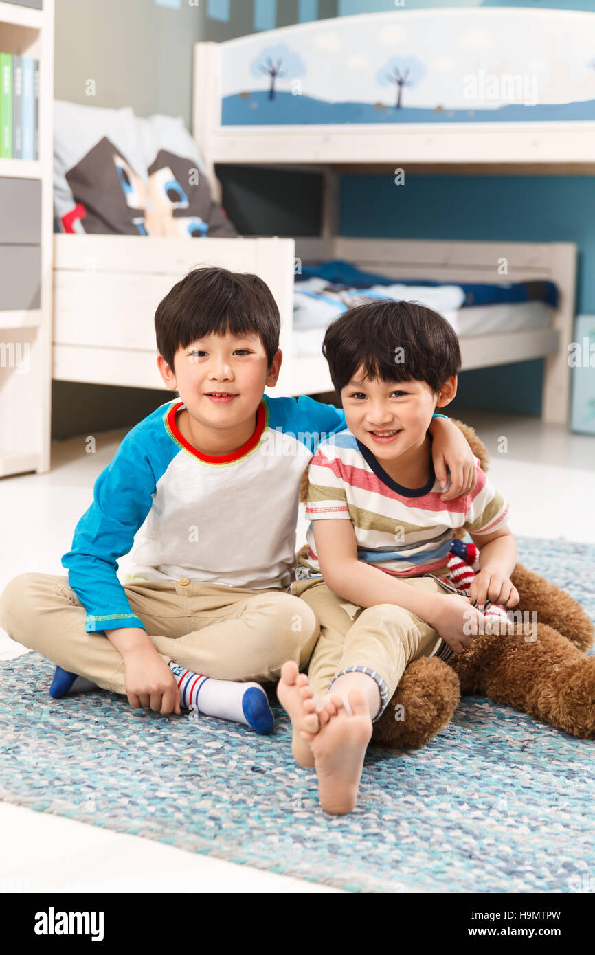 Two boys sitting on the carpet in the bedroom Stock Photo - Alamy
