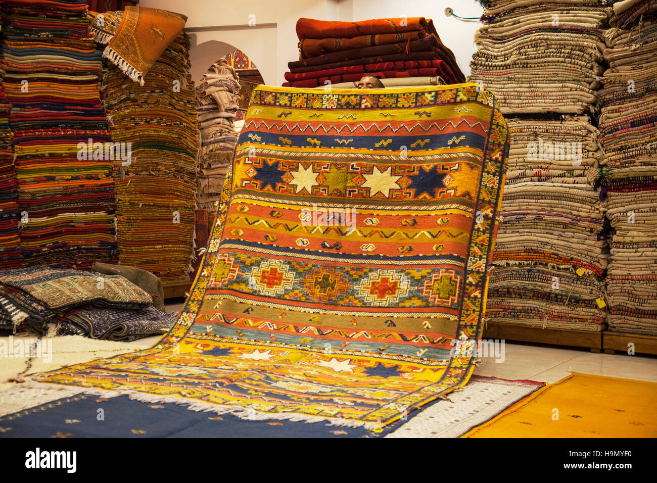Moroccan seller showing a carpets in Marrakesh Stock Photo - Alamy