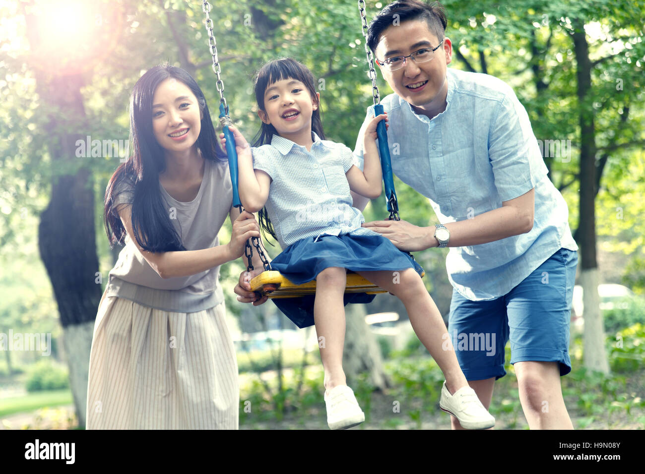 Happy family of three swing Stock Photo - Alamy