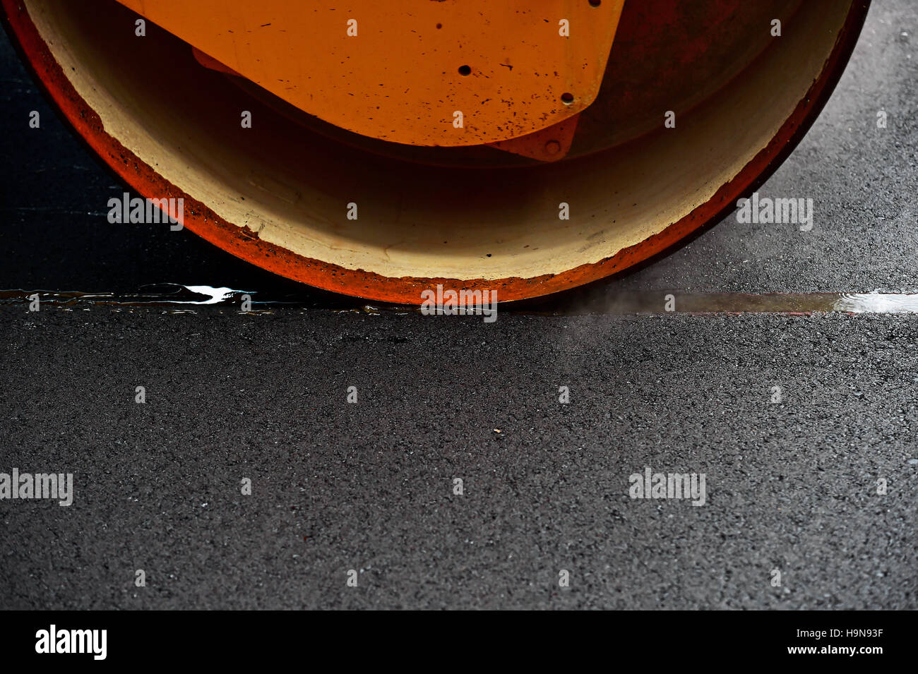 Asphalt paving with a steel wheel roller. Steam coming out from asphalt ...