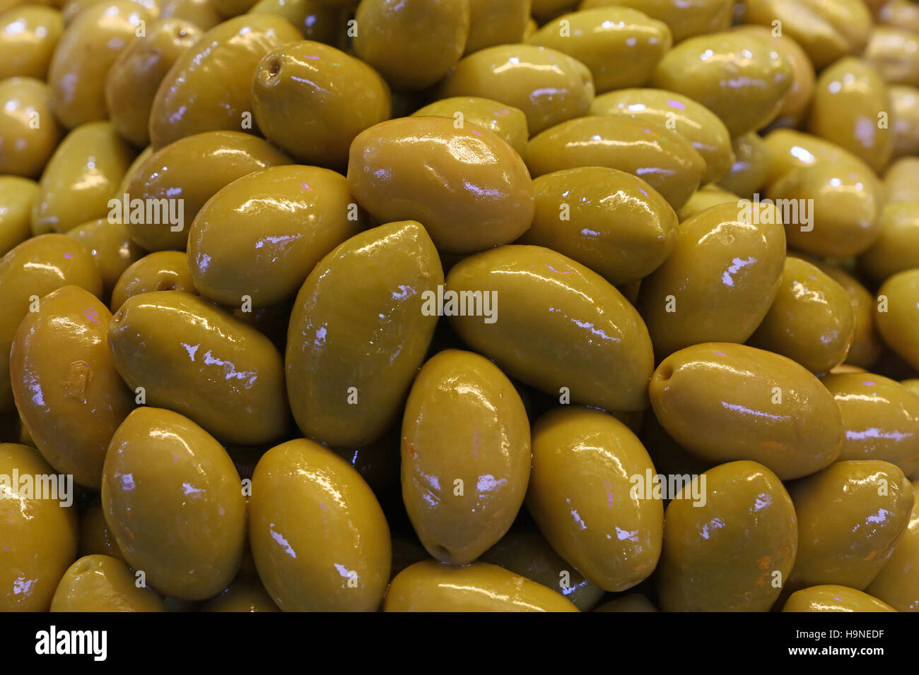 Green whole big Italian olives in oil close up background, retail ...