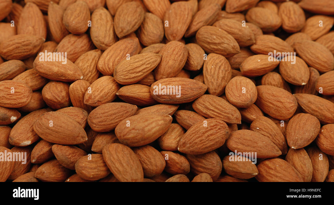 Whole raw brown almond nuts on retail market, close up, background, low ...