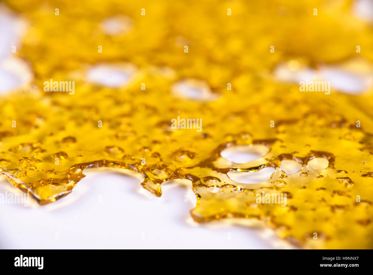 A piece of cannabis oil concentrate aka shatter isolated against white ...